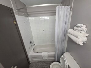 Casa de banho com banheira, sanita e porta-toalhas com toalhas.