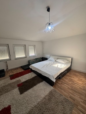 Quarto com cama, radiador, janela e luminária no teto.