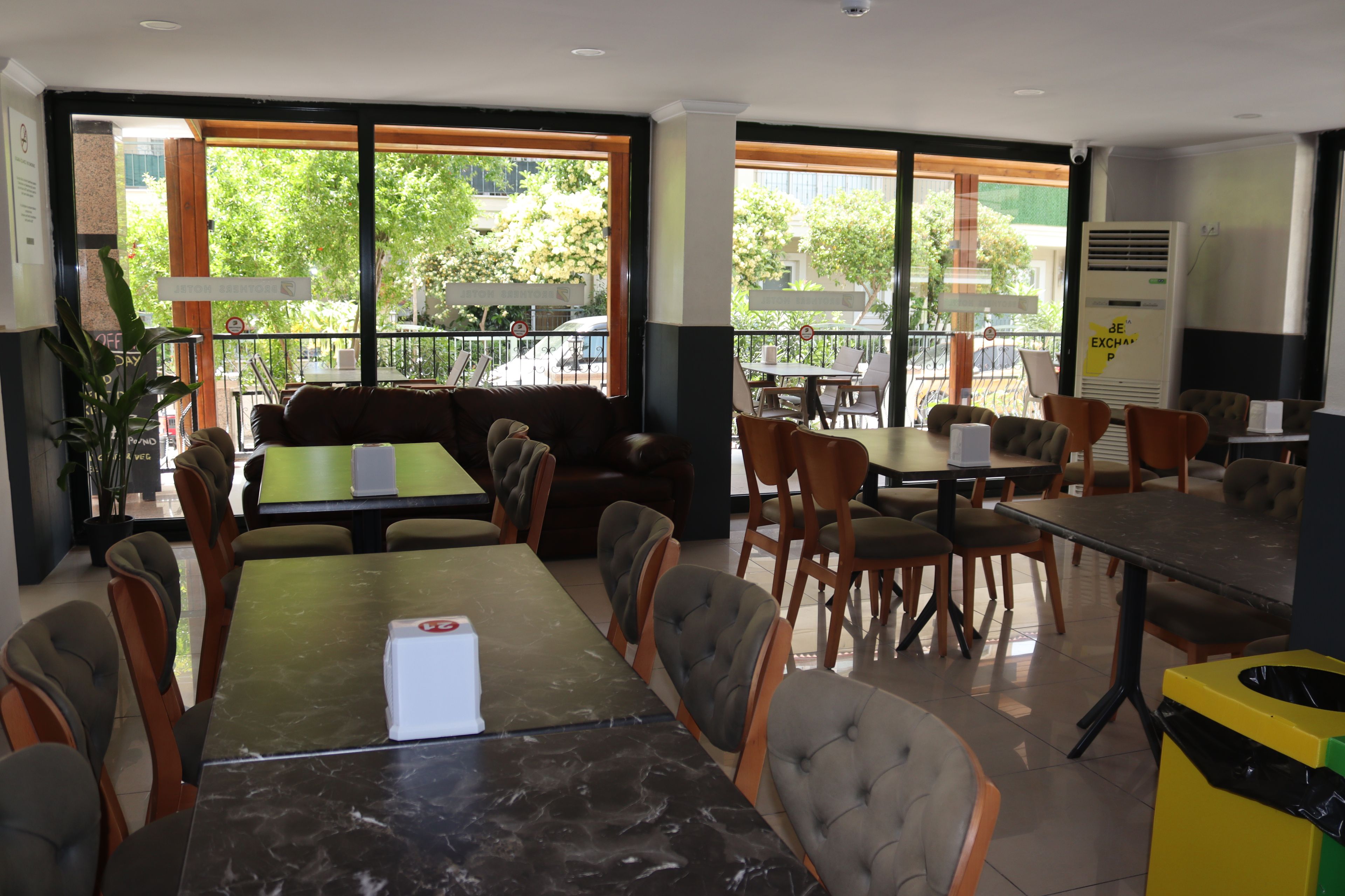Um restaurante com mesas internas, janelas amplas e vista para o exterior.