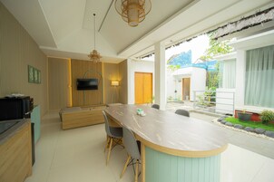 Cozinha moderna com ilha central, área de jantar com mesa e cadeiras, e vista para o jardim exterior.