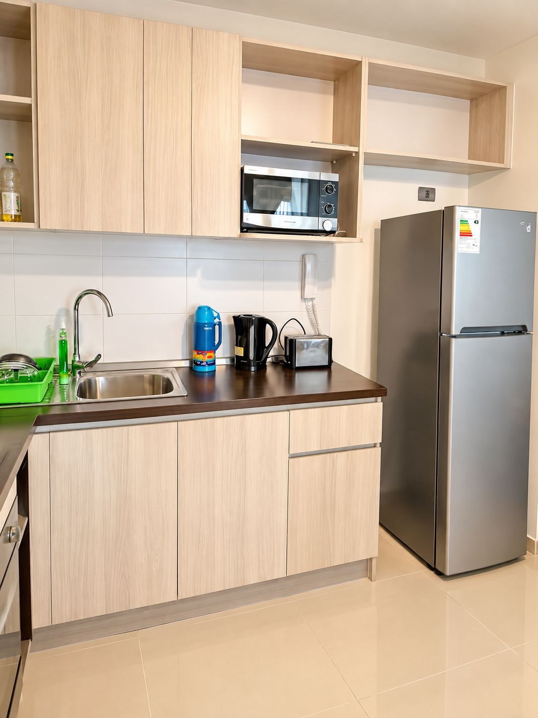 Uma cozinha moderna com armários de madeira, geladeira de aço inoxidável, micro-ondas e cafeteira.