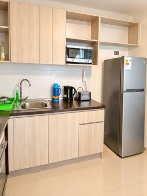 Uma cozinha moderna com armários de madeira, geladeira de aço inoxidável, micro-ondas e cafeteira.
