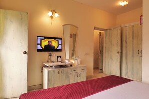 Quarto de hotel com cama, televisão na parede, cômoda e guarda-roupa.