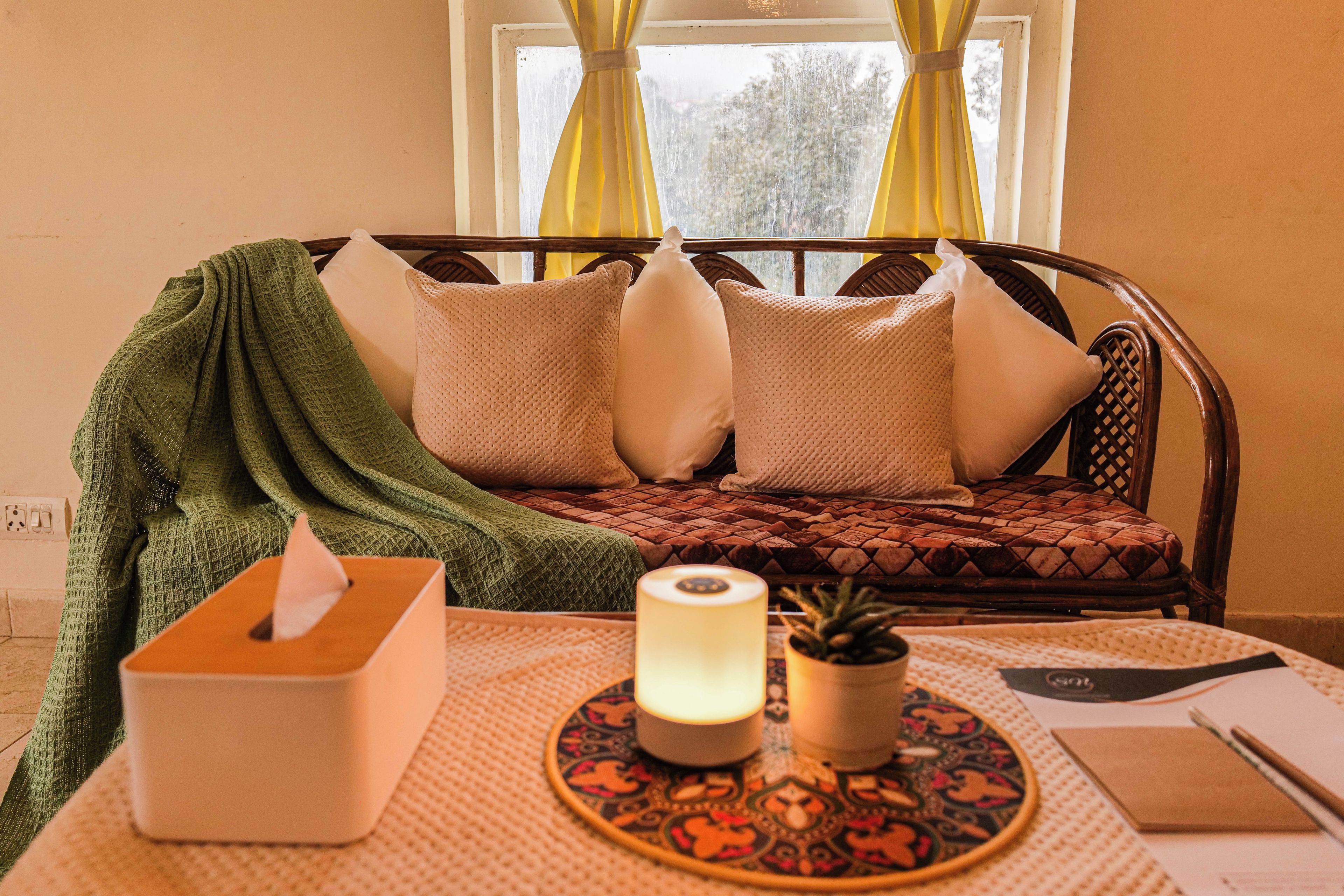 Um quarto aconchegante com uma cama, mesa de cabeceira com caixa de lenços, abajur e um prato decorativo.