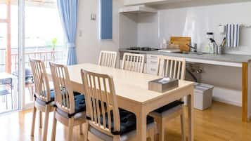 Cozinha moderna com área de refeições, cadeiras de madeira e vista para o exterior.