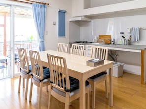 Cozinha moderna com área de refeições, cadeiras de madeira e vista para o exterior.