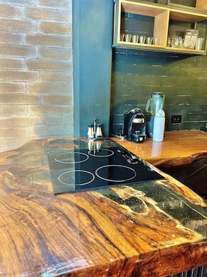 Cozinha com bancada de madeira, fogão por indução preto, liquidificador e cafeteira.