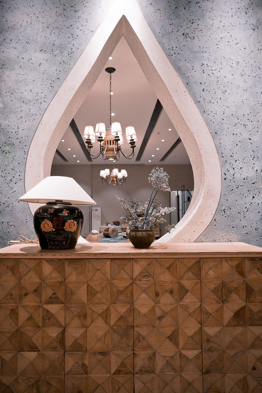Interior moderno com design geométrico na parede, uma luminária decorativa e um vaso de planta.