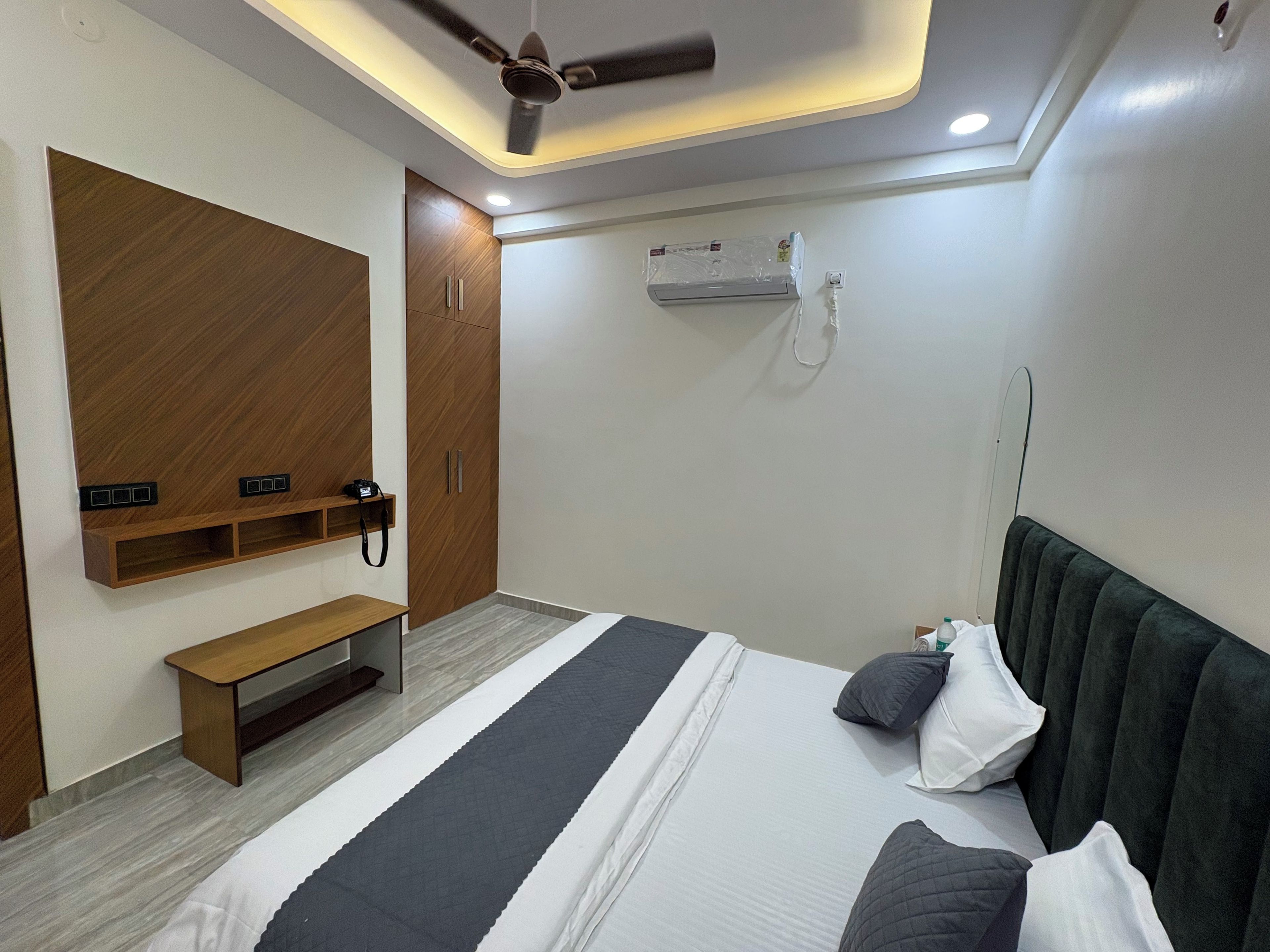 Quarto moderno com cama, mesa de cabeceira, guarda-roupa, ventoinha no teto e ar condicionado.