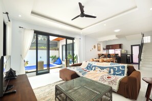 Uma sala de estar moderna com mesa de centro de vidro, sofá e ventilador de teto.