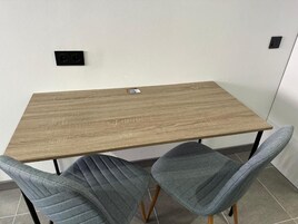Uma mesa retangular de madeira com duas cadeiras estofadas.