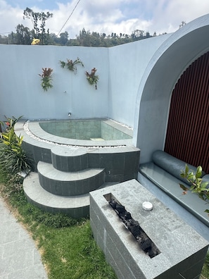 Uma área de spa com hidromassagem curvo, degraus de pedra e um espaço de estar com vista para a paisagem circundante.