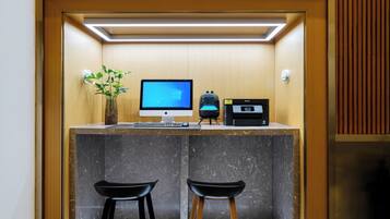 Espaço de trabalho moderno com computador de mesa, impressora e um vaso com plantas.