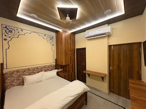 Quarto com cama, armário de madeira e ar condicionado.
