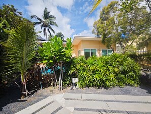 Um bairro residencial com uma casa, palmeiras e um jardim bem cuidado.
