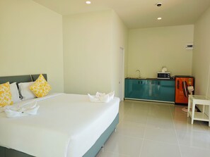 Quarto de hotel com cama, cozinha compacta e banheiro.
