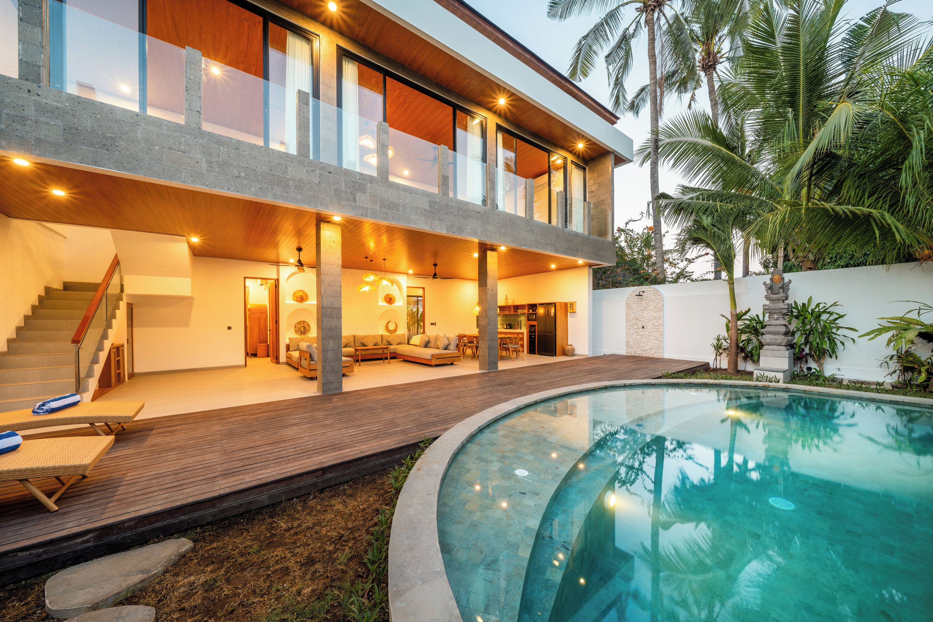 Uma casa moderna de dois andares com piscina, deck de madeira e escada que leva ao andar superior.