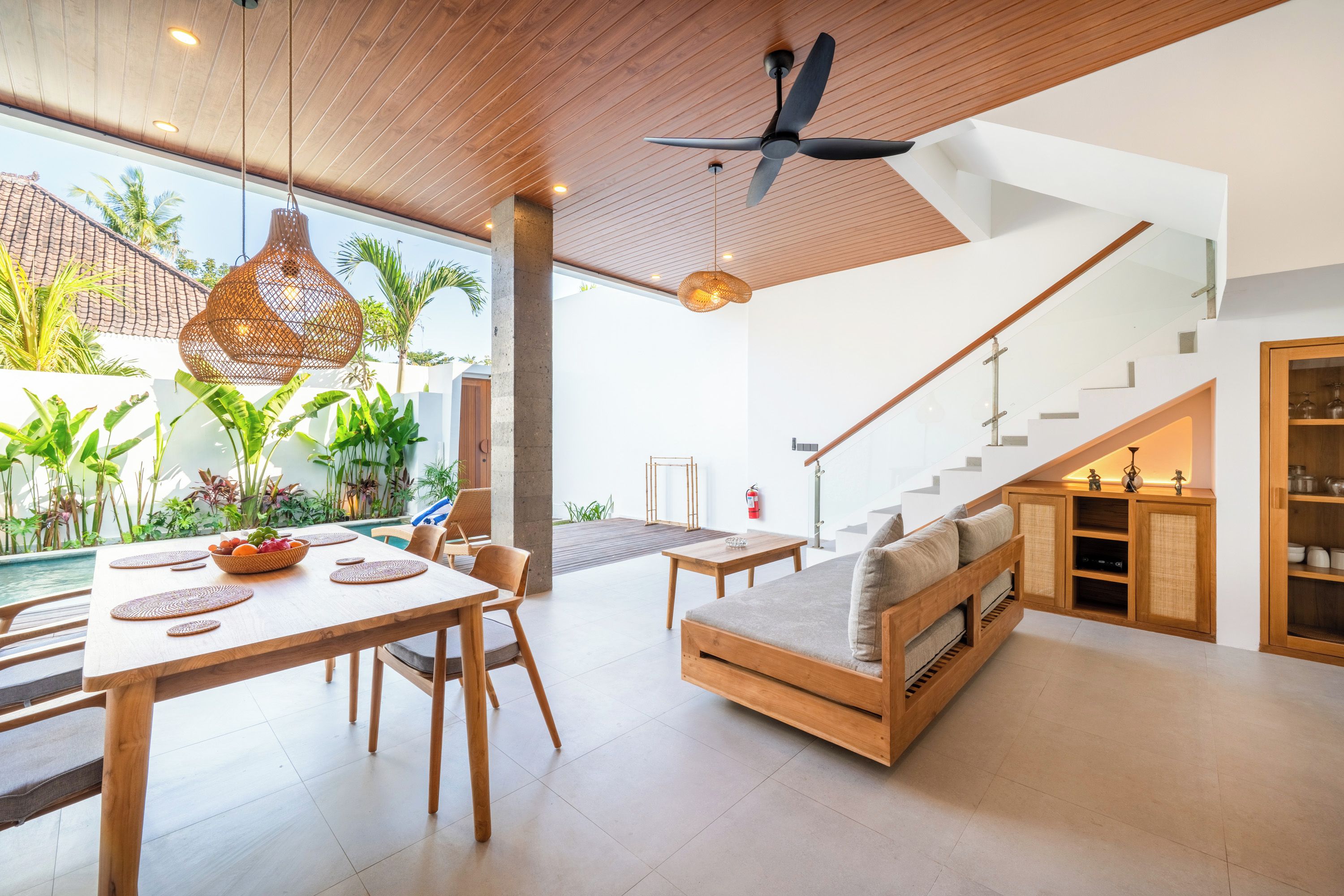 Um interior moderno com área de jantar, sofá, escada e vista para o exterior.