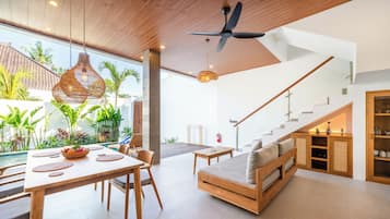 Um interior moderno com área de jantar, sofá, escada e vista para o exterior.