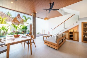 Um interior moderno com área de jantar, sofá, escada e vista para o exterior.