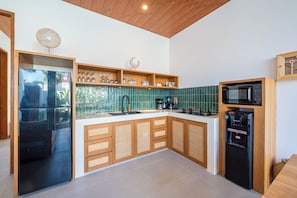 Cozinha moderna com armários de madeira, geladeira preta, micro-ondas e cafeteira.
