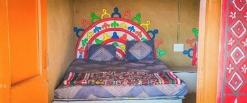 Uma cama com cabeceira colorida e edredom estampado.