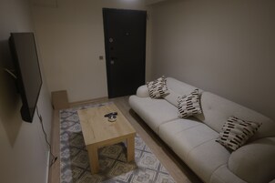 Uma sala de estar com sofá, mesa de centro e televisão.