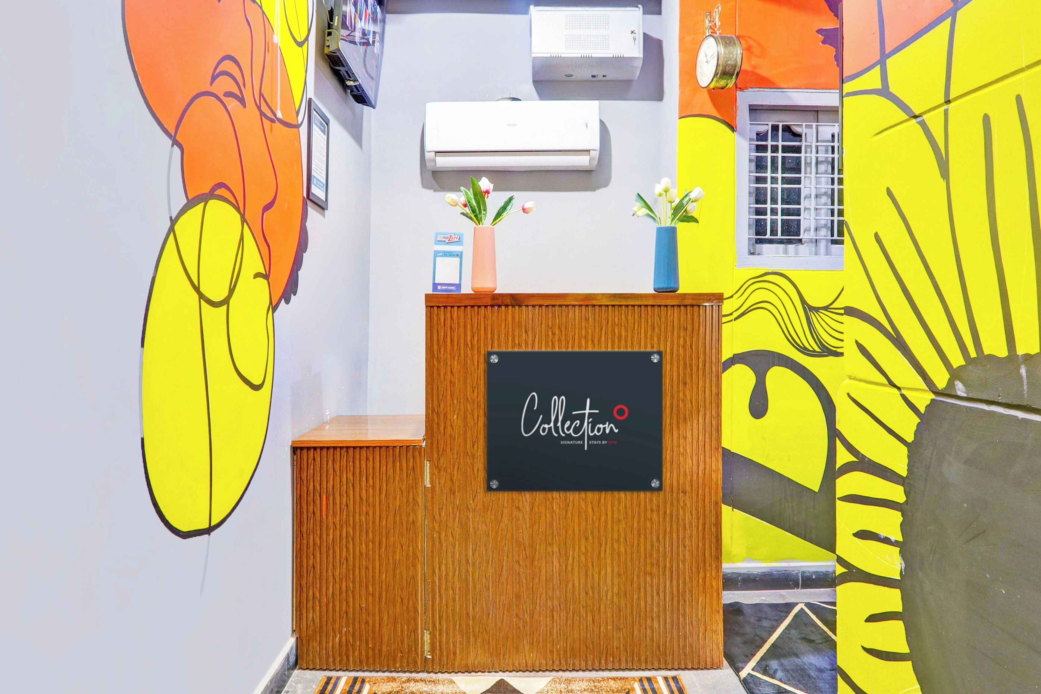 Bancada de recepção com placa, ar-condicionado fixado na parede e janela com vista.