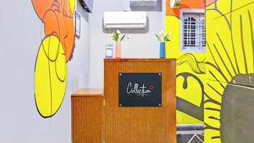 Bancada de recepção com placa, ar-condicionado fixado na parede e janela com vista.