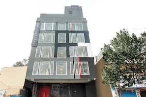 Um edifício de vários andares com porta vermelha e várias janelas.
