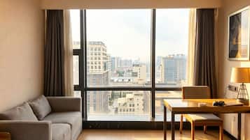 Quarto de hotel com uma janela grande, um sofá, uma escrivaninha e uma cama.
