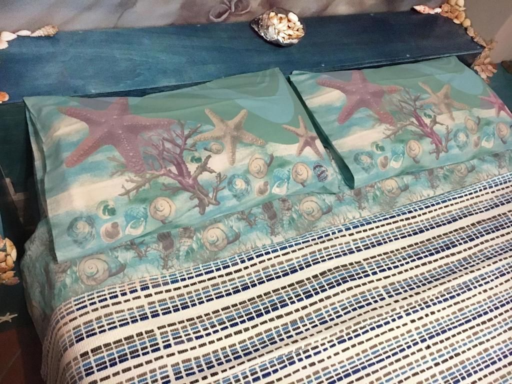 Uma cama com colcha azul e branca listrada e dois travesseiros com tema náutico.
