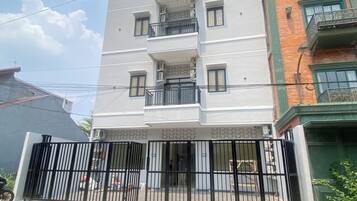 Edifício residencial com vários andares, portão fechado, varandas e aparelhos de ar condicionado.