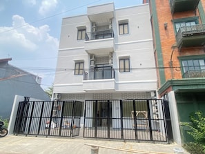 Edifício residencial com vários andares, portão fechado, varandas e aparelhos de ar condicionado.