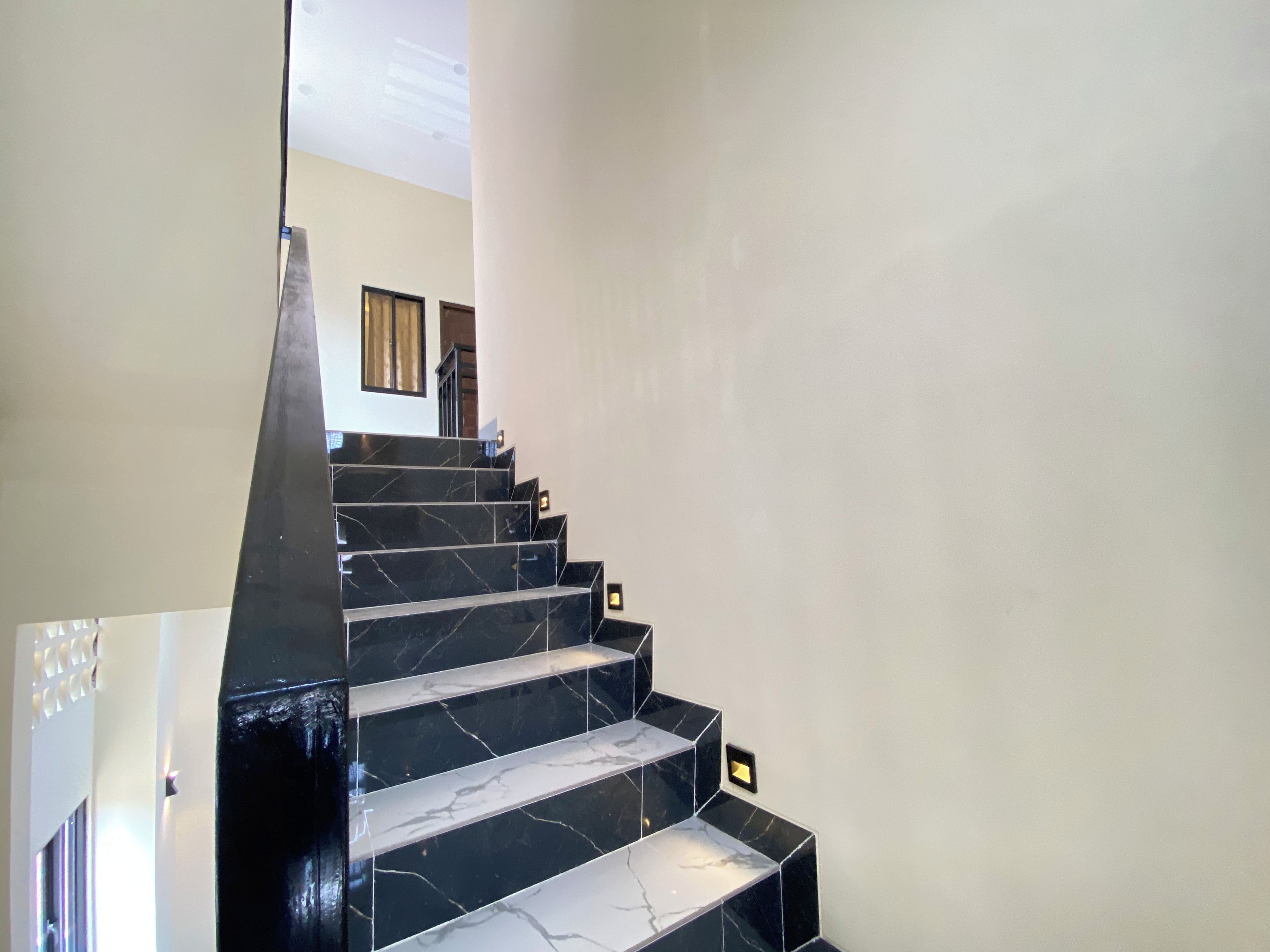 Escadaria com degraus de mármore preto e design moderno.