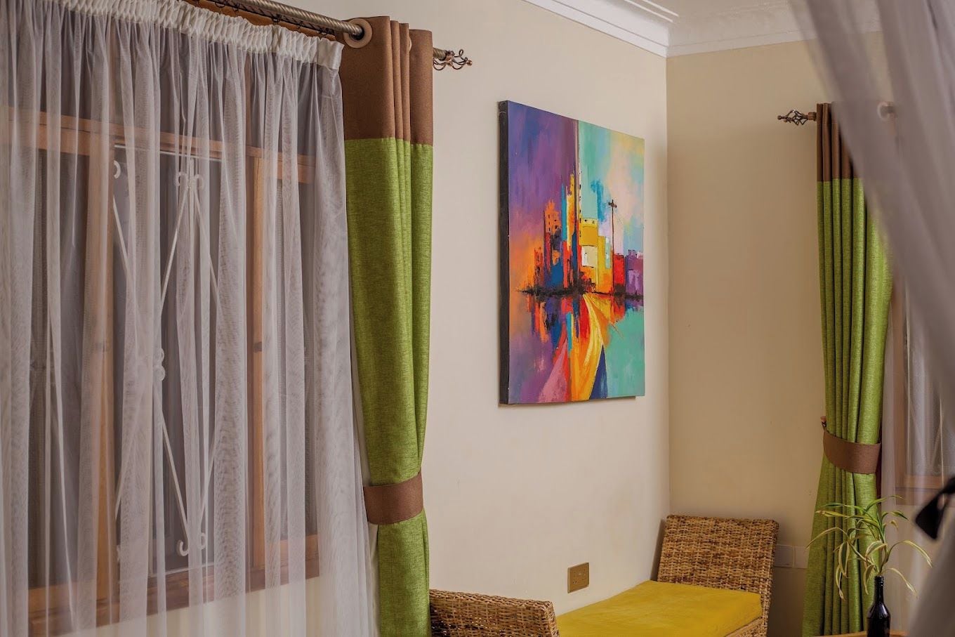 Quarto com cama, quadro na parede e janela com cortinas.