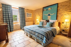 Quarto com cama, duas luminárias de cabeceira, um quadro e uma janela com cortinas.