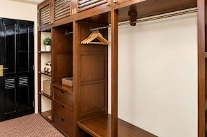 Um closet espaçoso de madeira com prateleiras, gavetas e cabideiro.