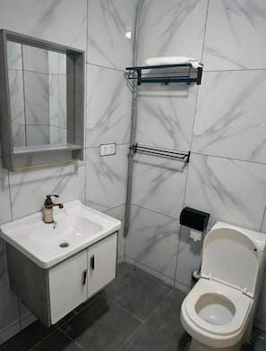 Um banheiro com pia branca, vaso sanitário e espelho.