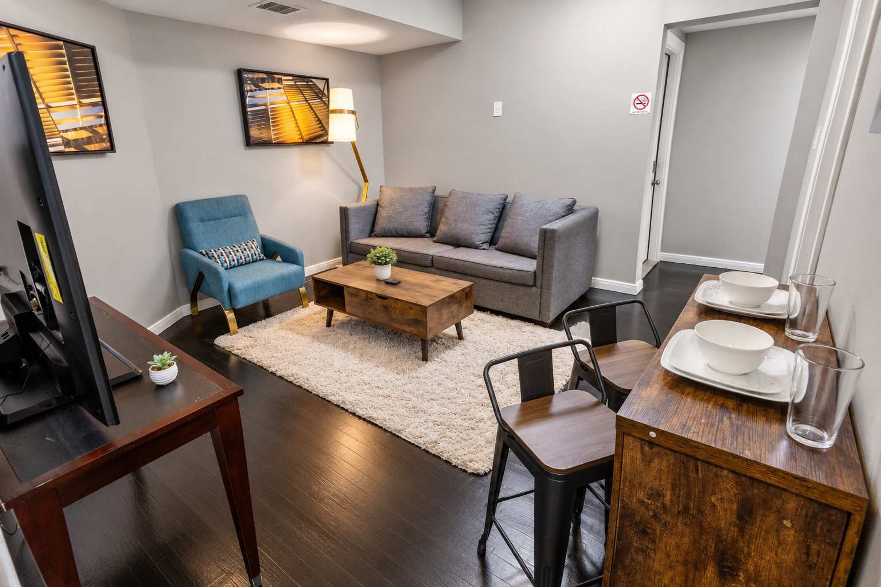 Uma sala moderna com sofá, poltrona, mesa de centro e um espaço de jantar com cadeiras e mesa.