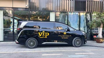 Um carro preto com a marca 'VIP METROPOLO JINJIANG HOTELS' estacionado em frente a um edifício com grandes janelas.