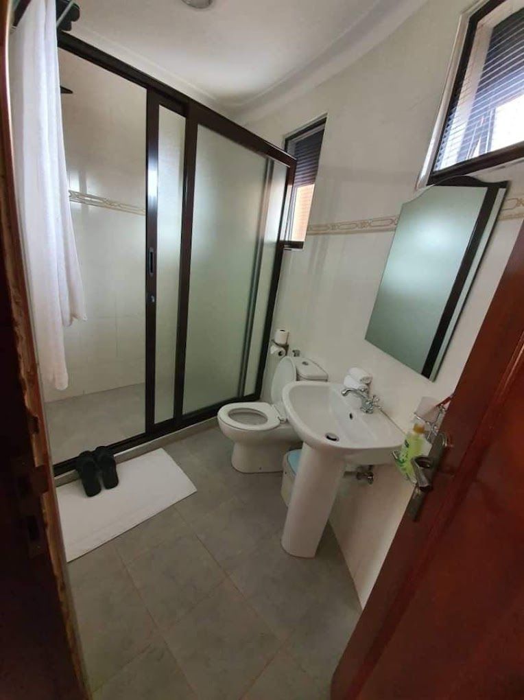 Casa de banho com chuveiro, sanita e lavatório.