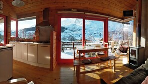 Interior de uma cabana de madeira com cozinha, sala de jantar e lareira.