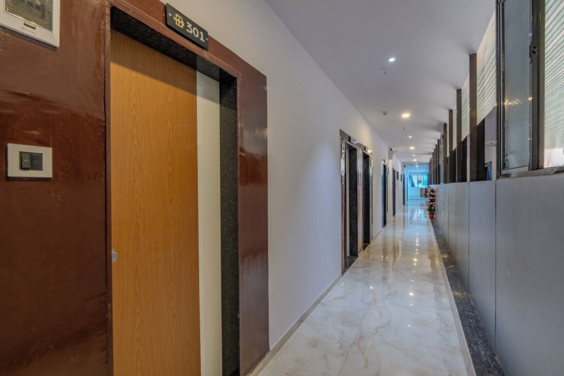 Corredor de hotel com porta de madeira marcada '301' e piso de mármore.