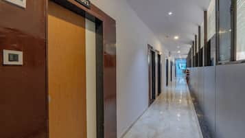 Corredor de hotel com porta de madeira marcada '301' e piso de mármore.