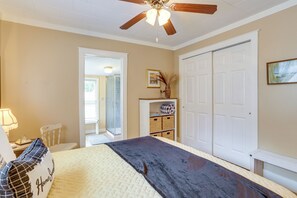 Quarto com cama, ventoinha no teto, porta e janela.