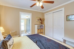 Quarto com cama, ventoinha no teto, porta e janela.