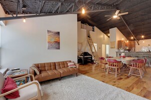 Uma sala ampla com um sofá marrom, um tapete branco e uma mesa de jantar com cadeiras.