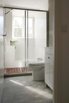 Uma casa de banho moderna com chuveiro, sanita e janela que permite entrada de luz natural.