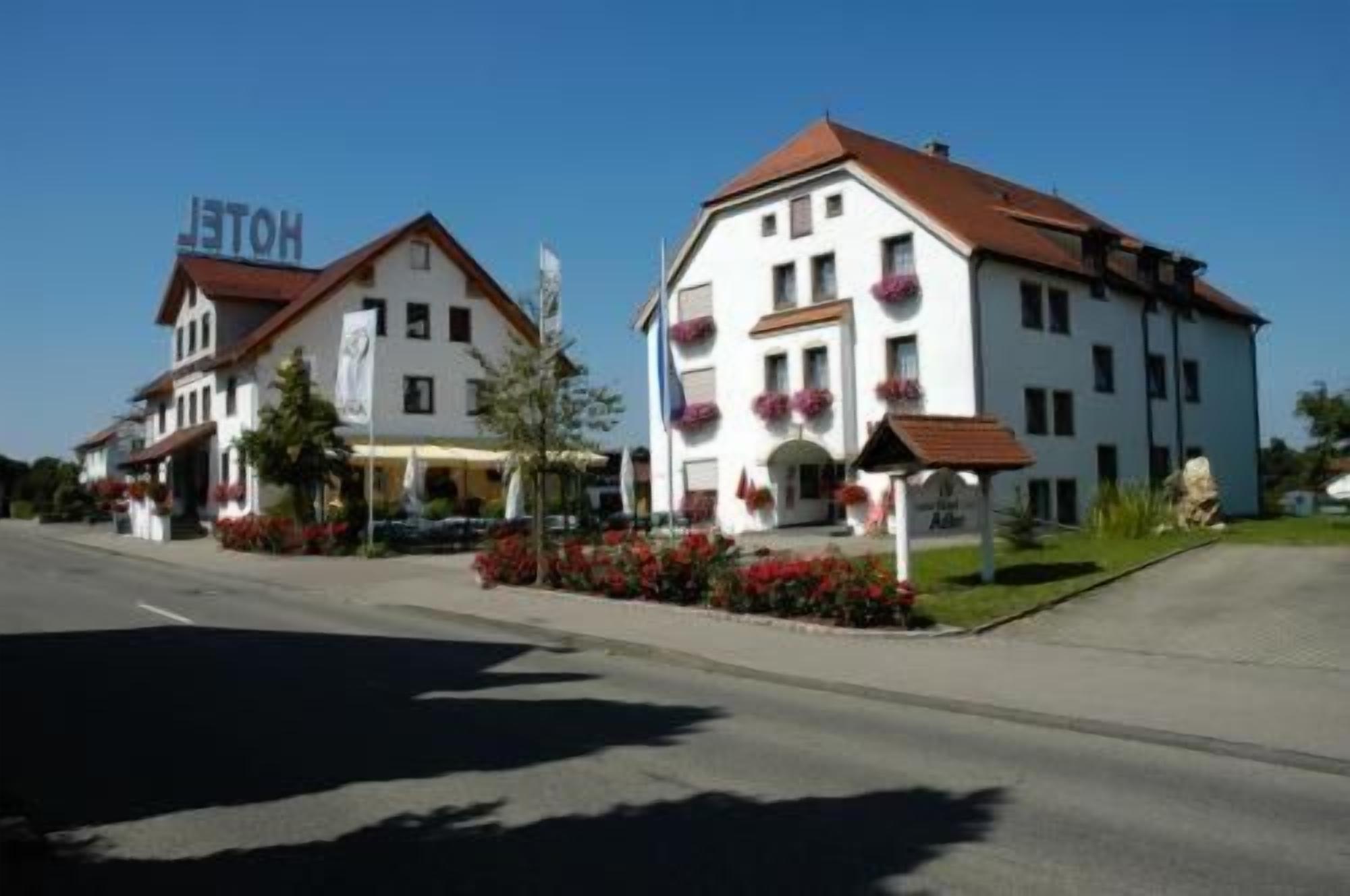 Um hotel com telhado vermelho, paredes brancas e uma placa.